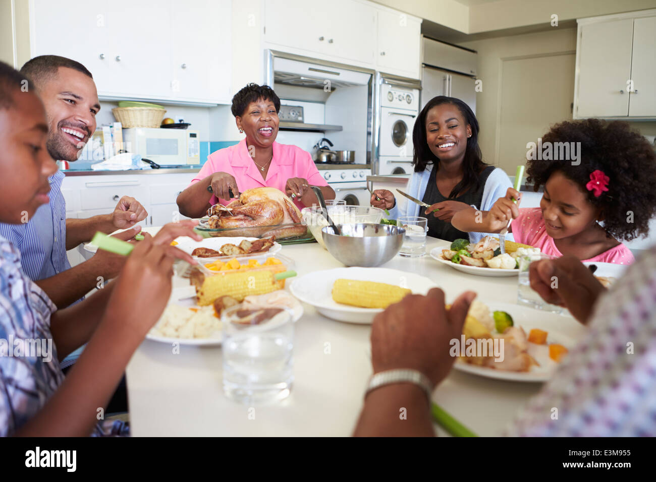 Multi-Generation Family Sitting Around Table Eating Meal Stock Photo ...