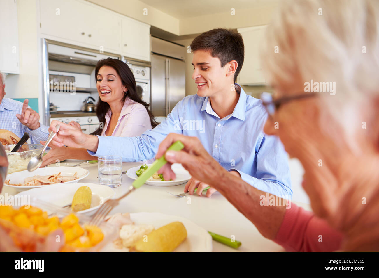 Multi-Generation Family Sitting Around Table Eating Meal Stock Photo ...