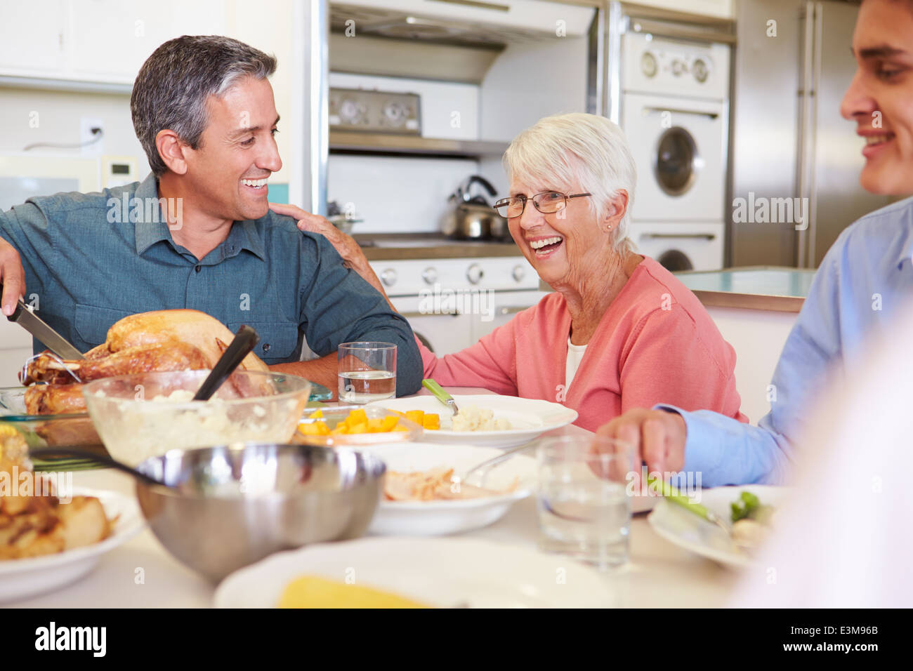 Multi-Generation Family Sitting Around Table Eating Meal Stock Photo ...