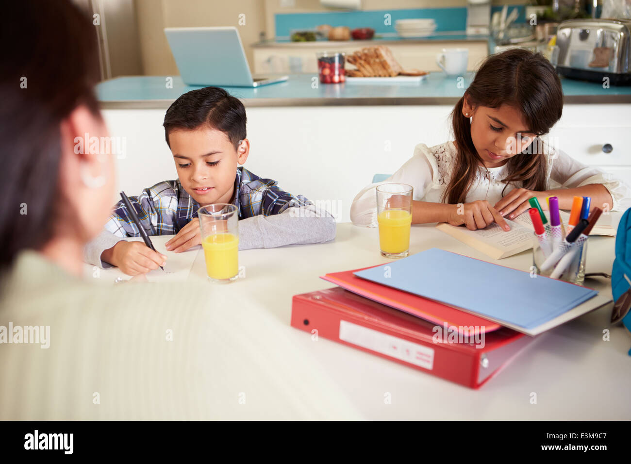 Mother Helping Children With Homework At Table Stock Photo - Alamy