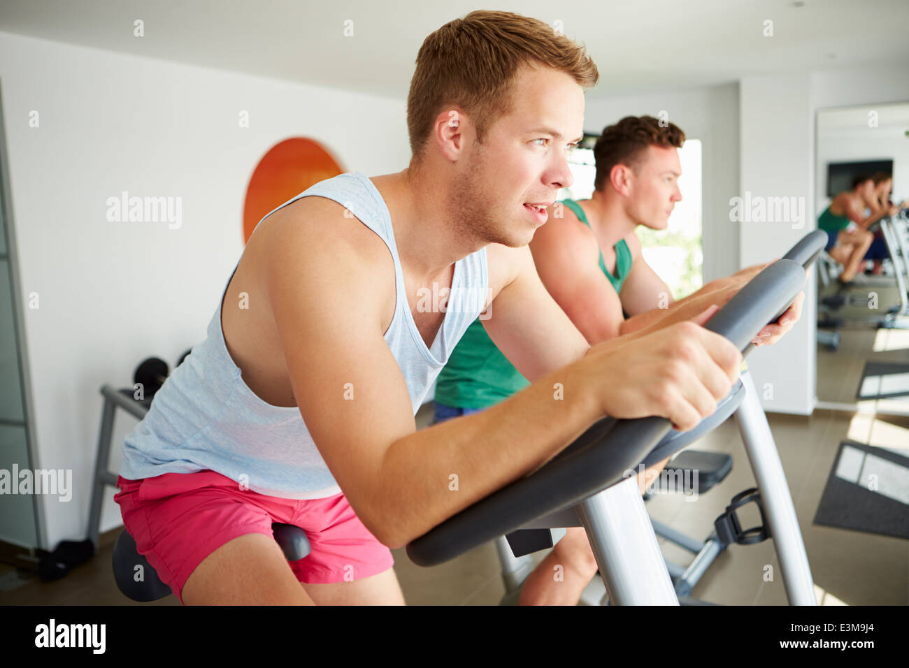 Two Young Men Training In Gym On Cycling Machines Together Stock Photo ...
