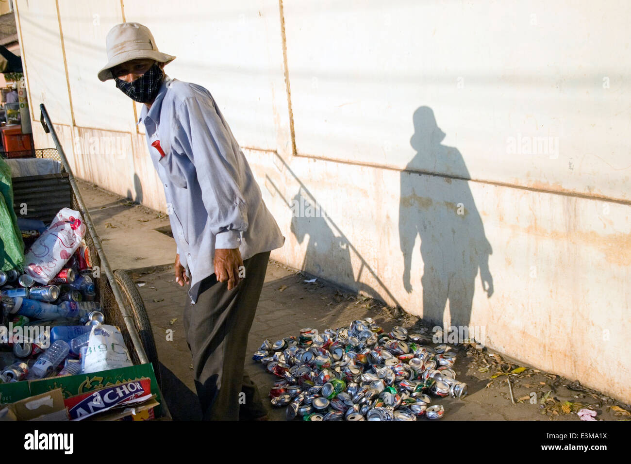 A scavenger man is collecting cans on a city street in Phnom Penh ...