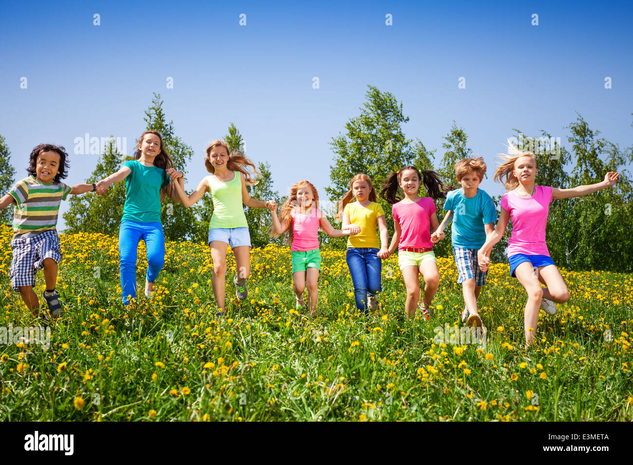 Playful children run, hold hands in green field Stock Photo - Alamy