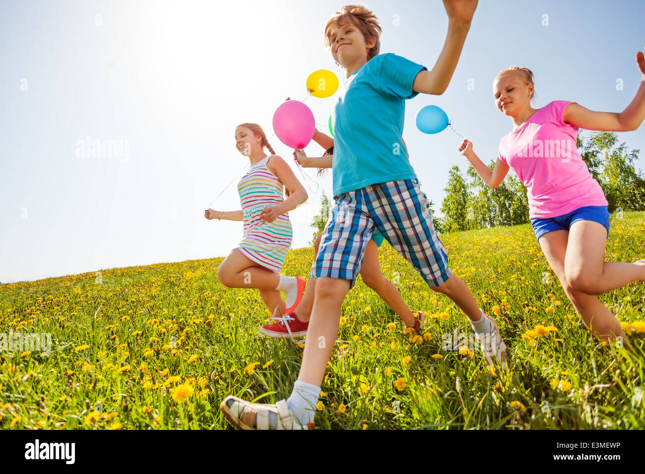 Happy children with balloons run in green field Stock Photo - Alamy
