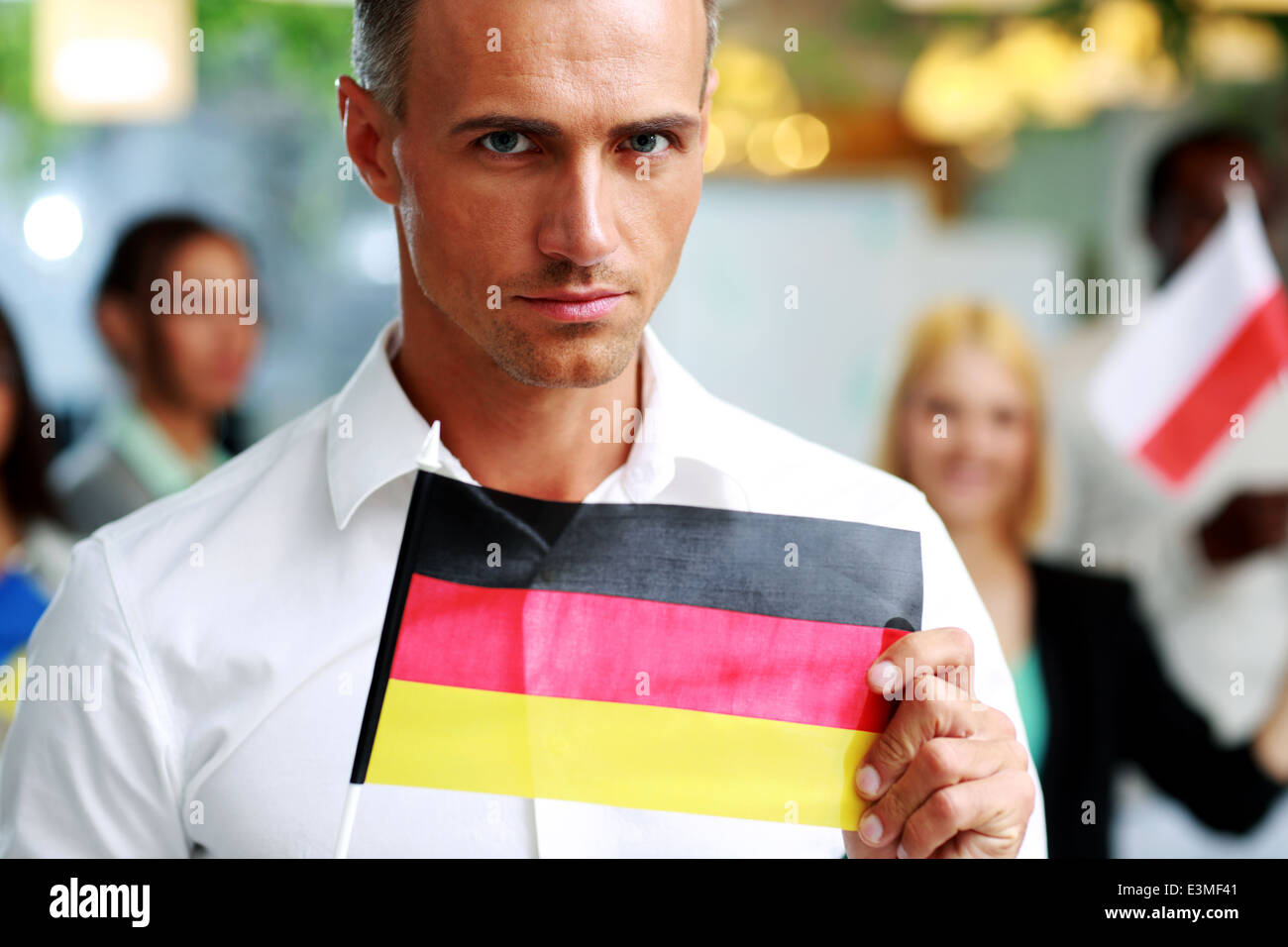 Handsome businessman holding flag of Germany in front of colleagues ...