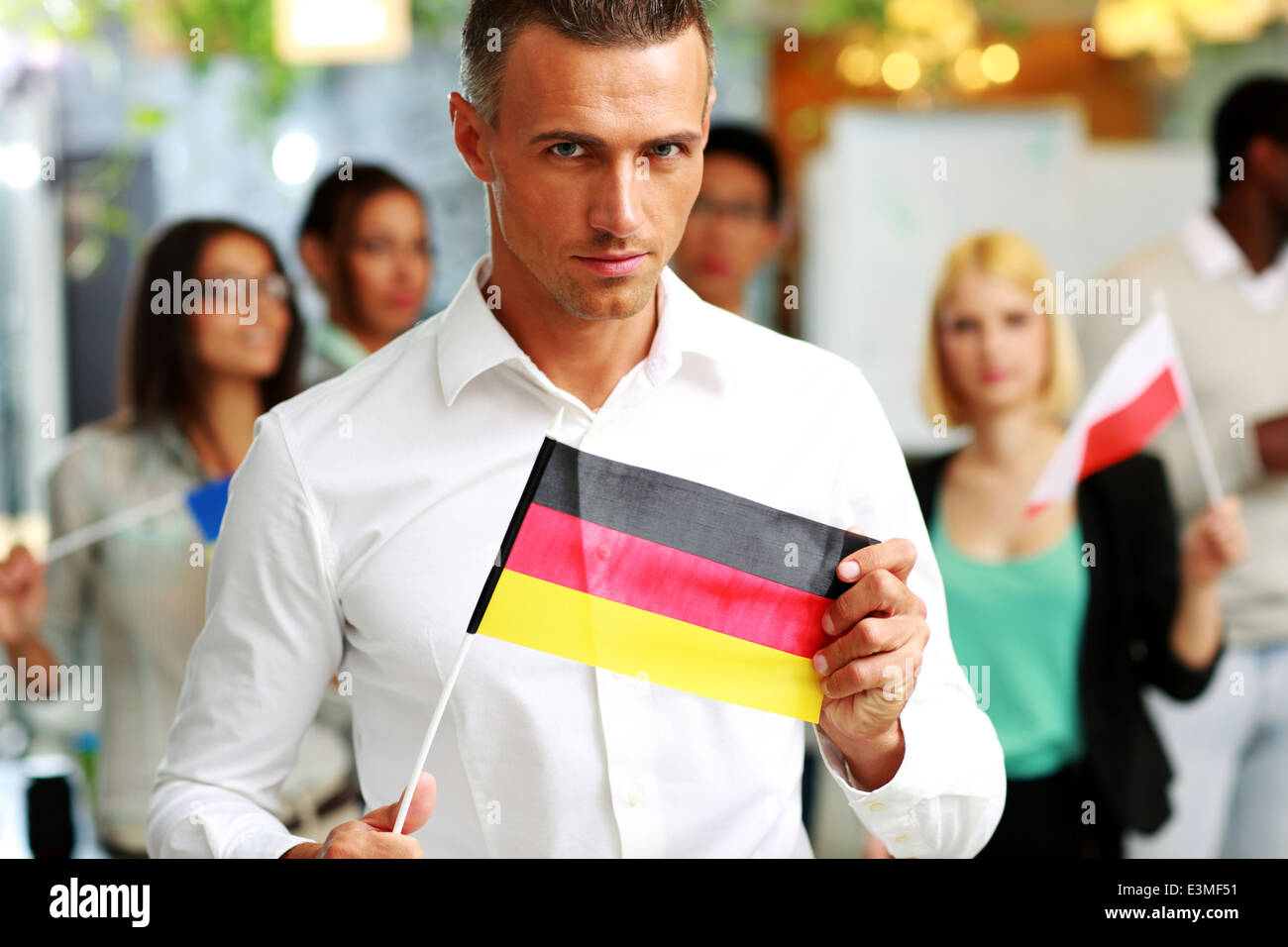Confident businessman holding flag of Germany in front of colleagues ...