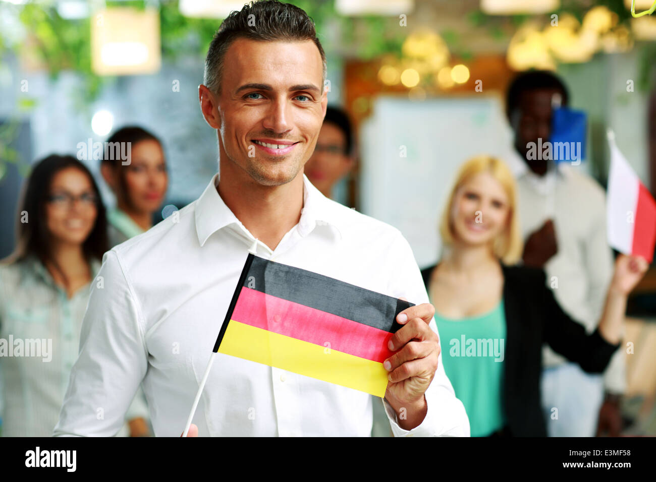 Happy businessman holding flag of Germany in front of colleagues Stock ...