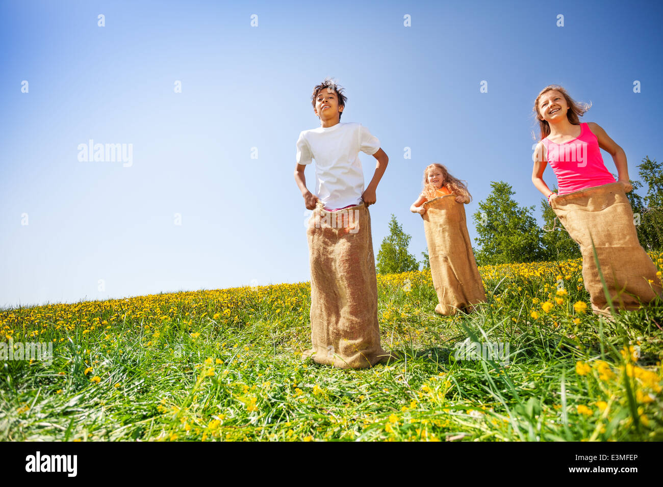 Happy children jumping in sacks during play Stock Photo - Alamy