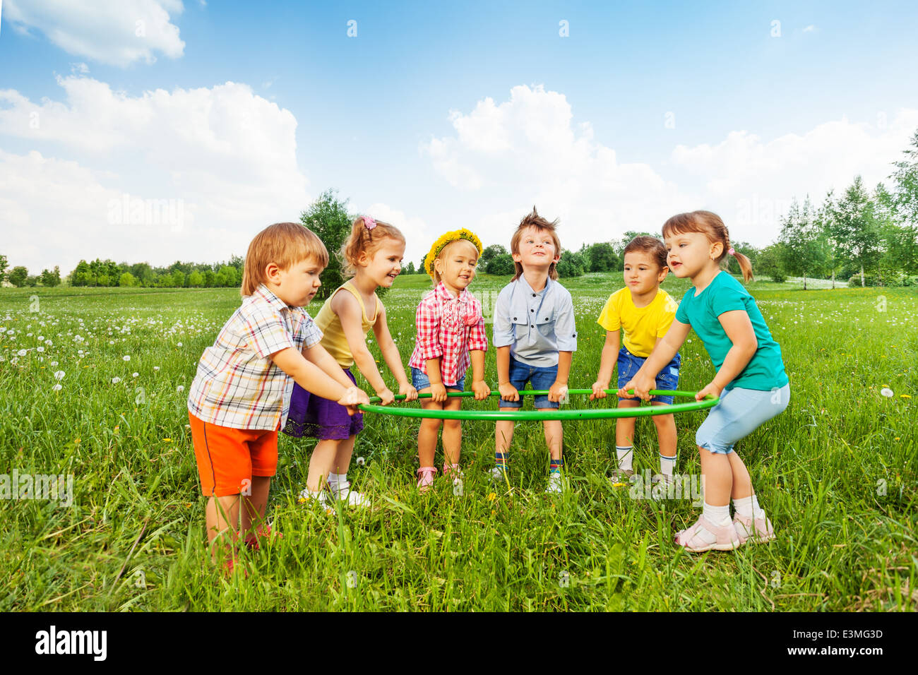 Smiling children holding one hoop together Stock Photo - Alamy