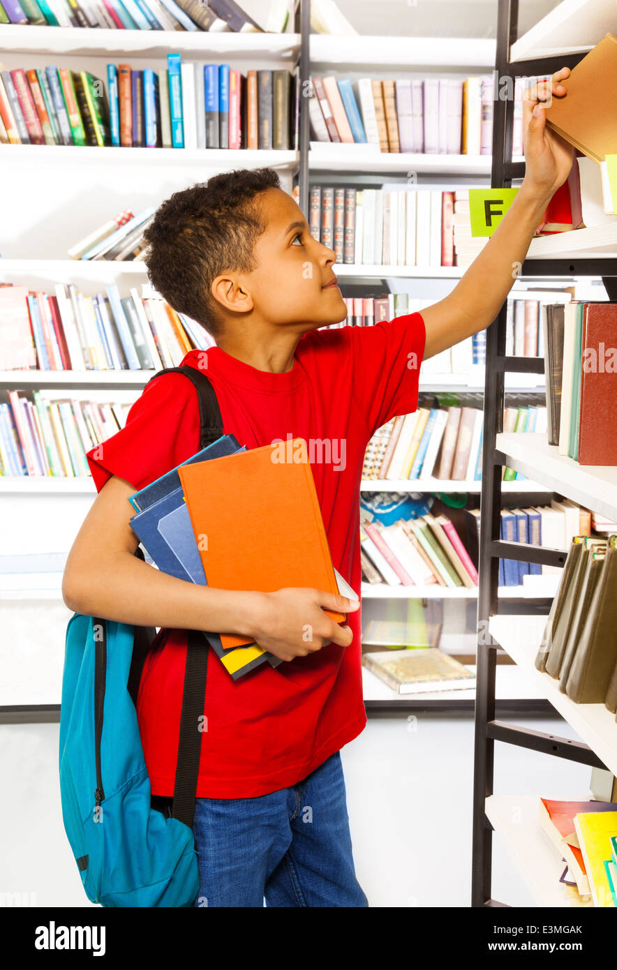 Boy searching books on library bookshelf Stock Photo - Alamy