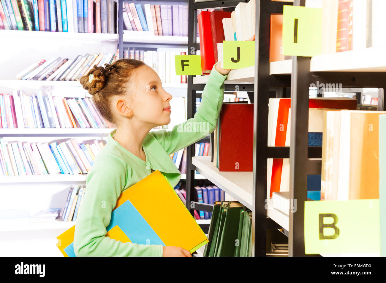 Girl looking and searching books in library Stock Photo - Alamy