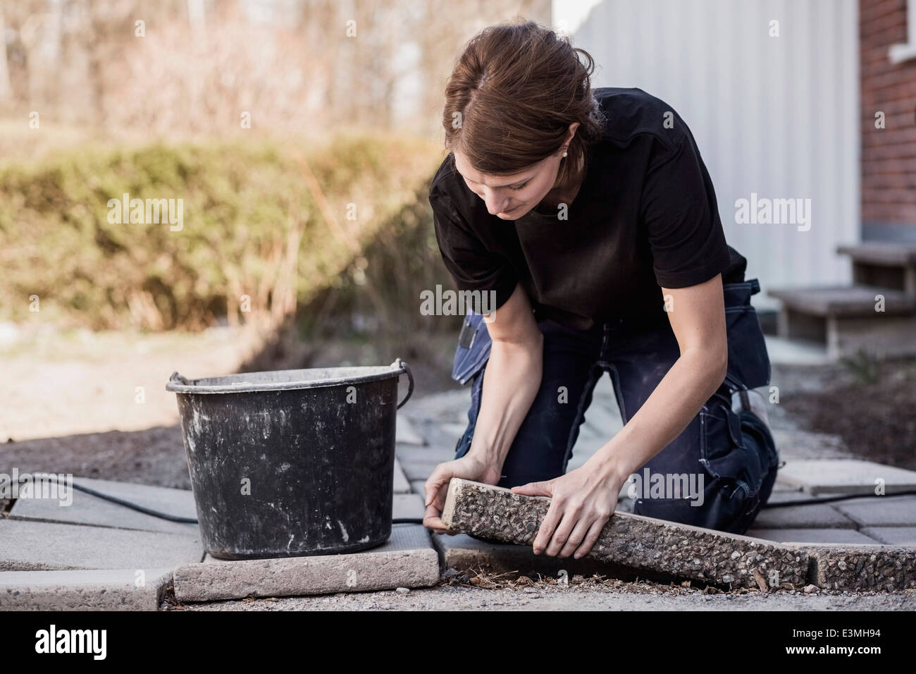 Female carpenter positioning stone tile in yard Stock Photo - Alamy