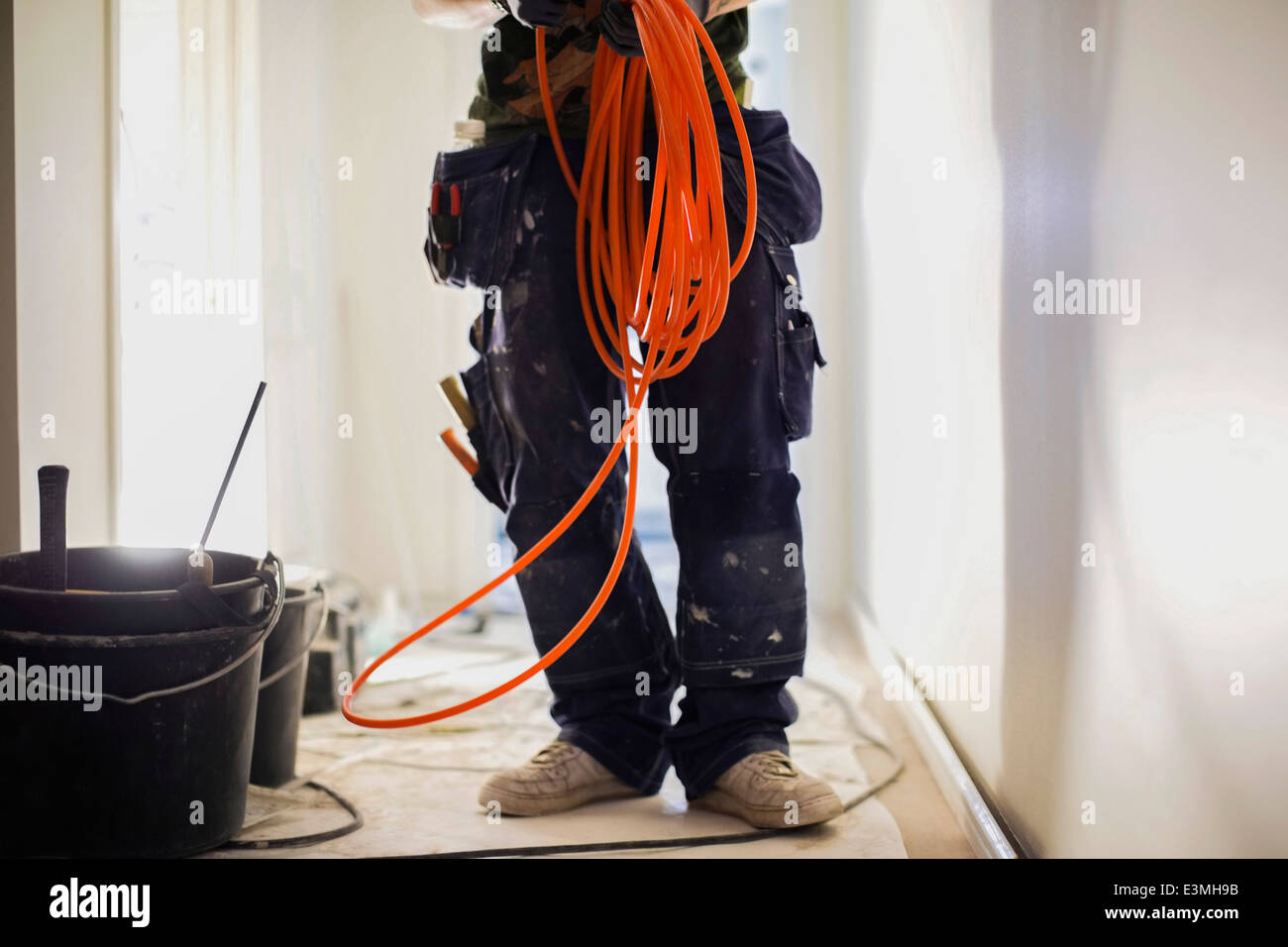 Low section of male carpenter holding wire cables at site Stock Photo ...