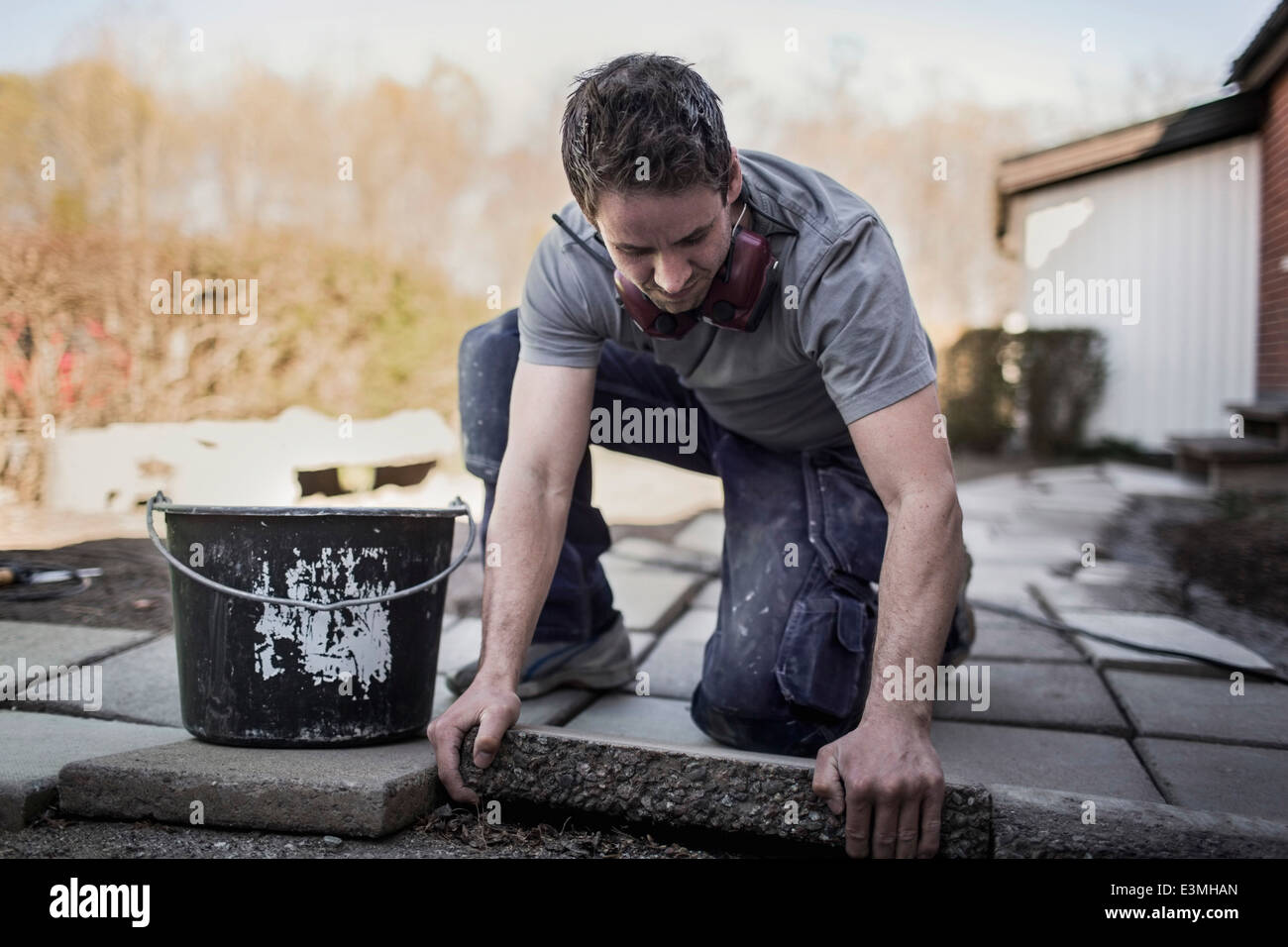 Carpenter positioning stone tile in yard Stock Photo - Alamy