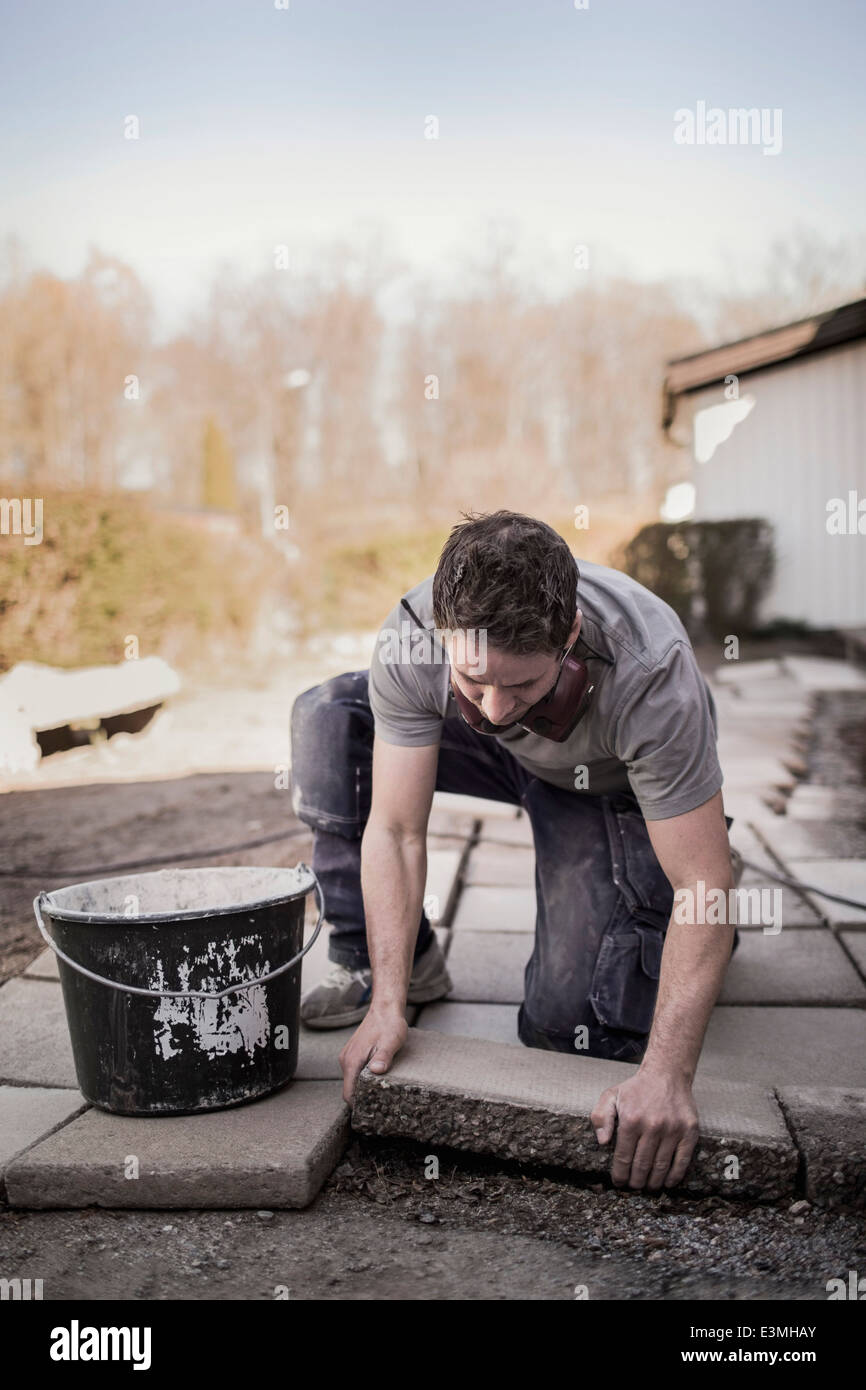 Male carpenter positioning stone tile in yard Stock Photo - Alamy