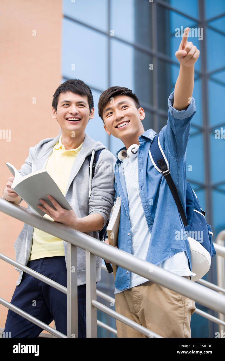 Male college students pointing outside library Stock Photo - Alamy