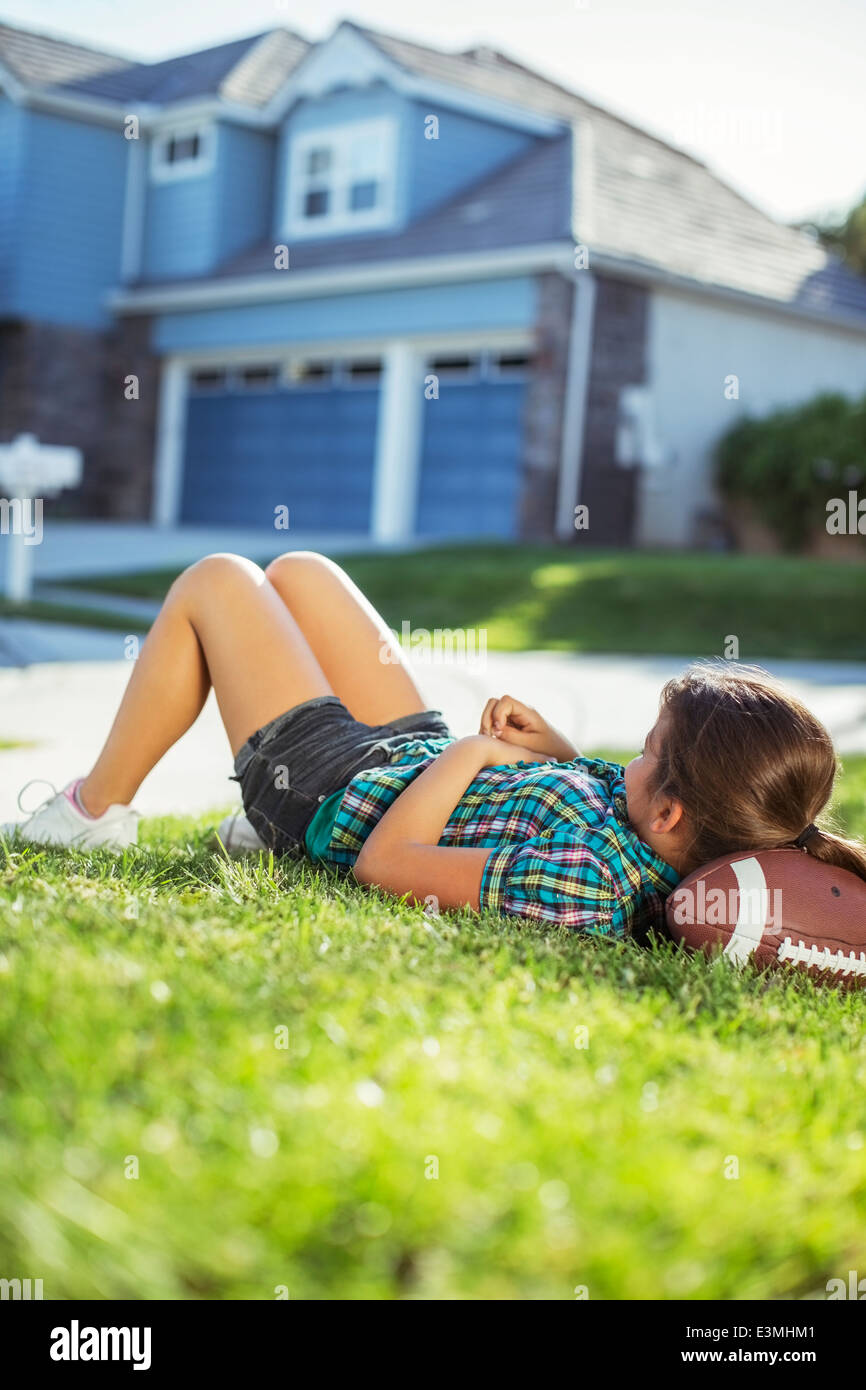 Girl laying on football in grass outside house Stock Photo - Alamy