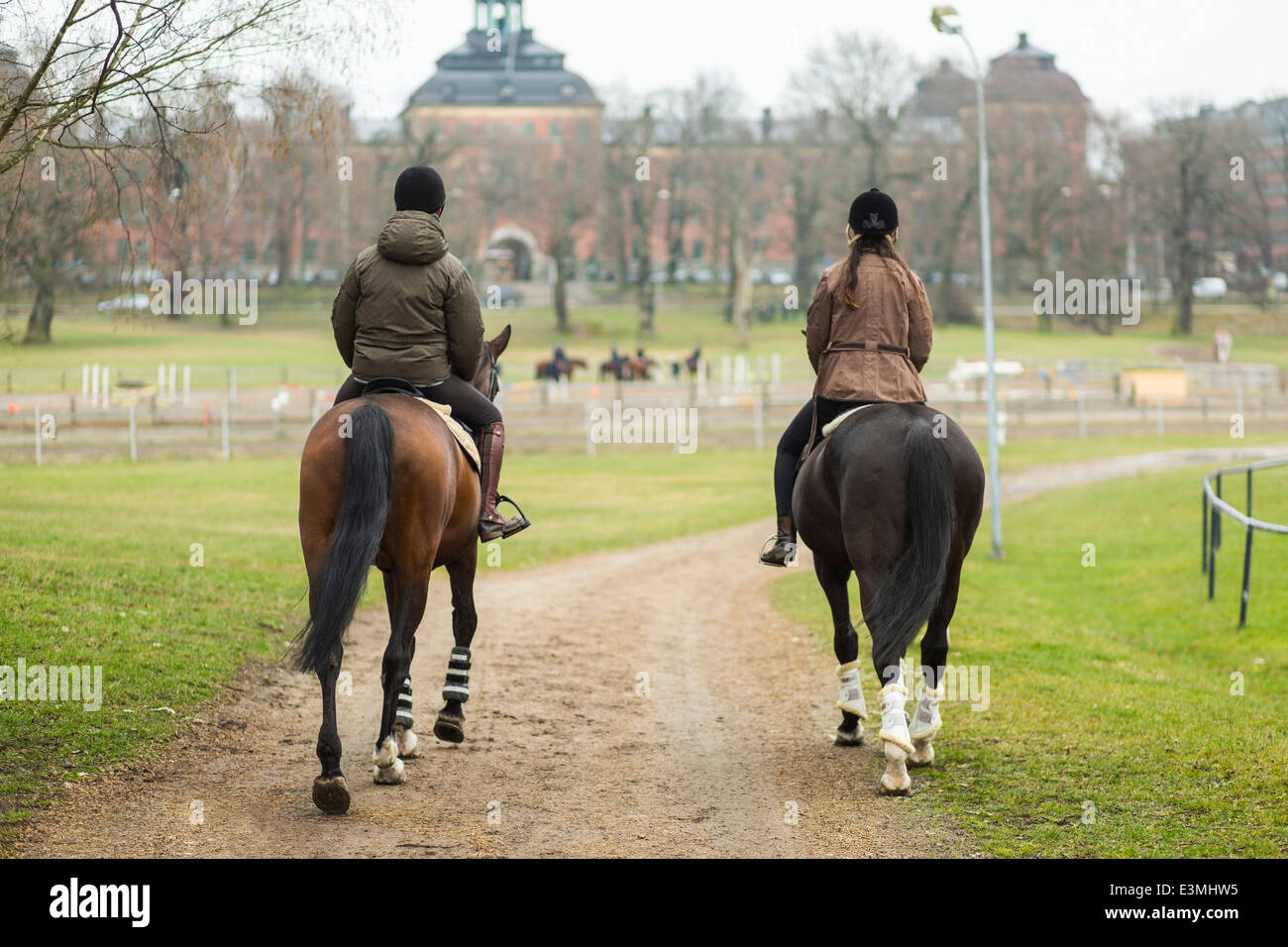 Full length rear view of young couple riding horses on dirt road Stock ...