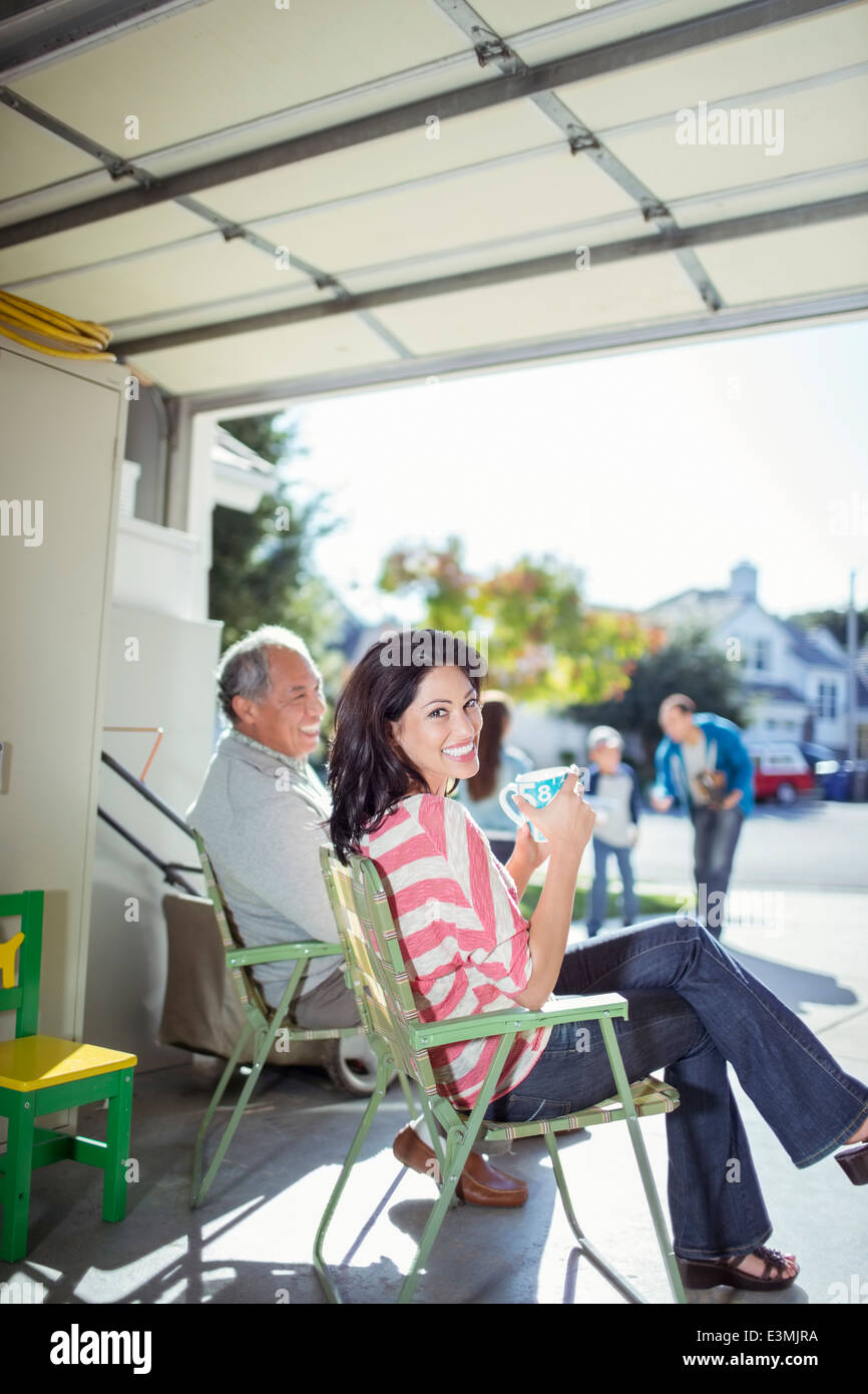 Portrait of smiling woman drinking coffee in garage Stock Photo - Alamy