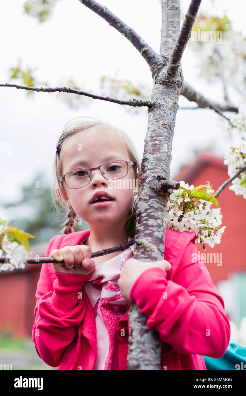 Portrait of girl with down syndrome holding tree branch in yard Stock ...