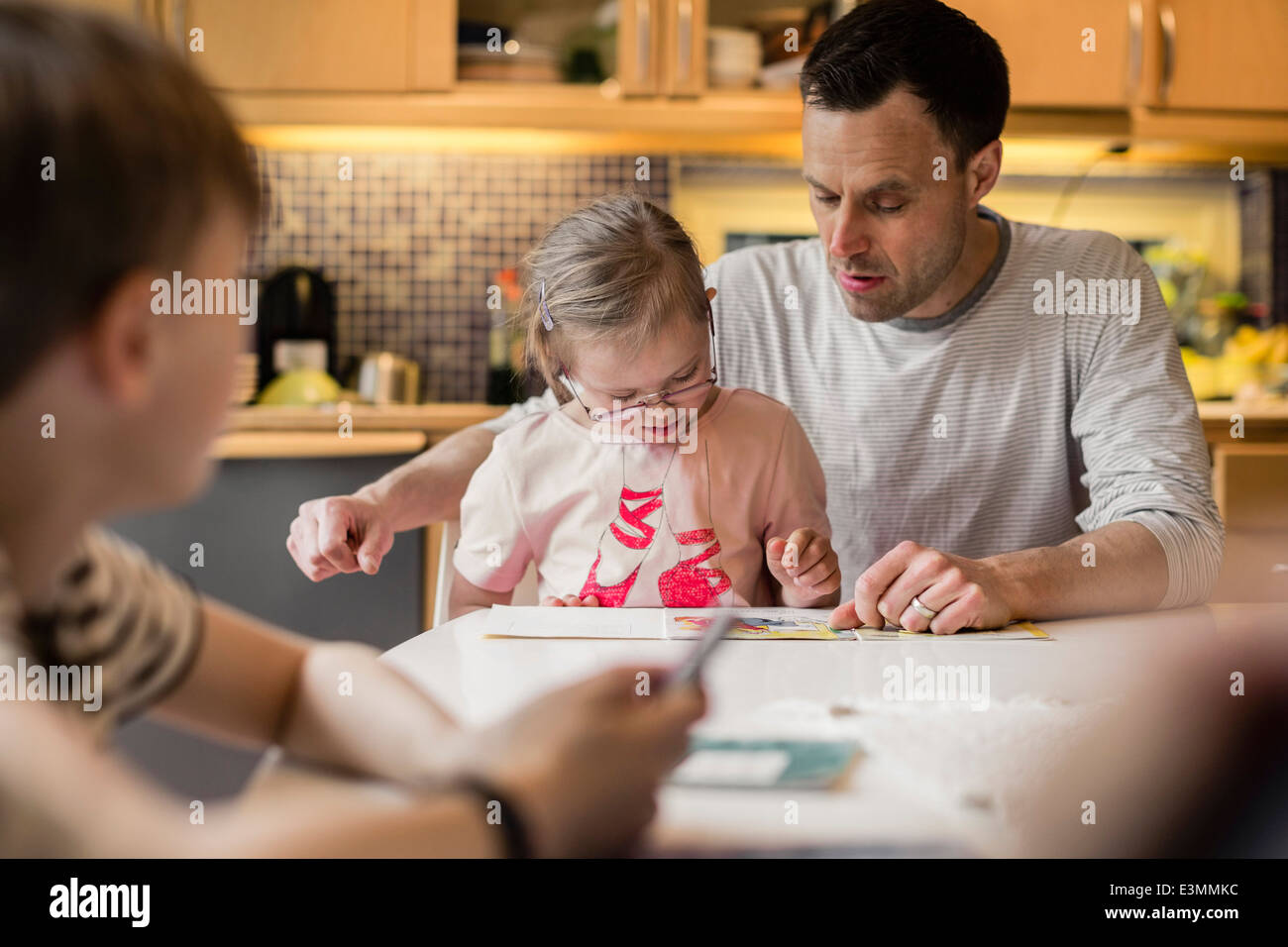 Father teaching daughter with son in foreground at home Stock Photo - Alamy