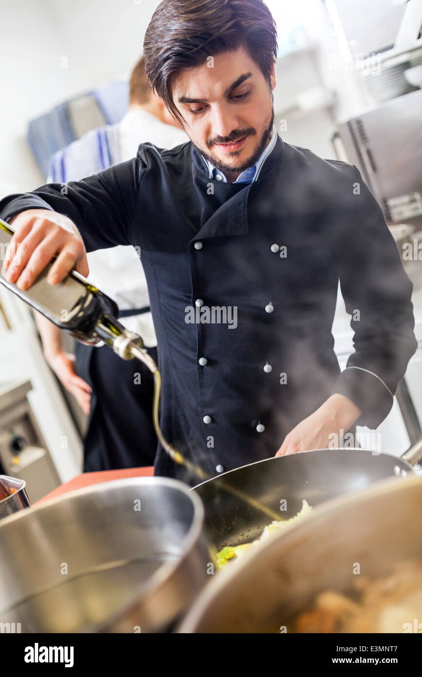 Professional chef in a commercial kitchen cooking a vegetable stir fry ...