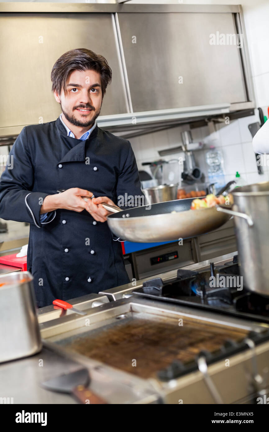 Professional chef in a commercial kitchen cooking a vegetable stir fry ...