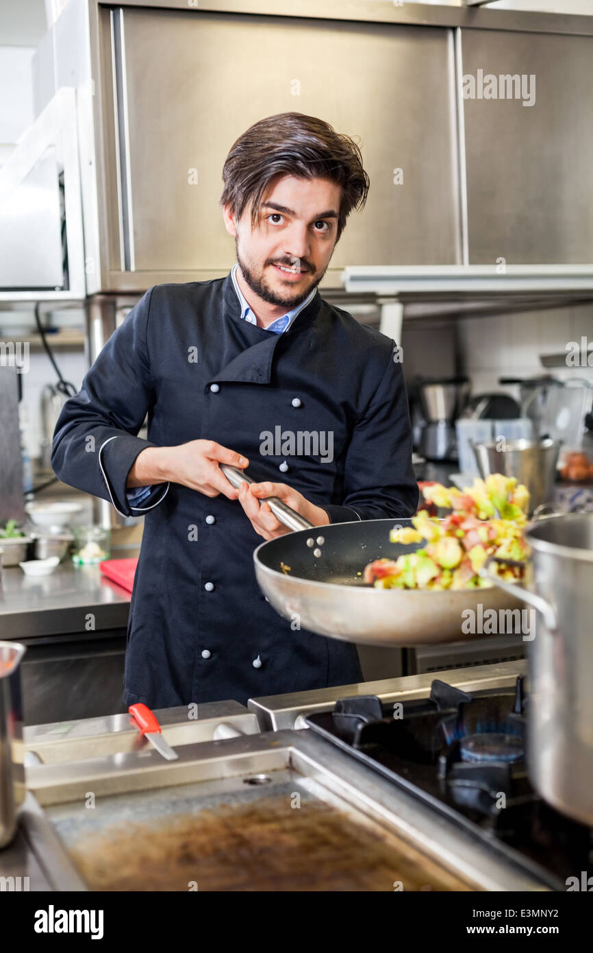 Professional chef in a commercial kitchen cooking a vegetable stir fry ...