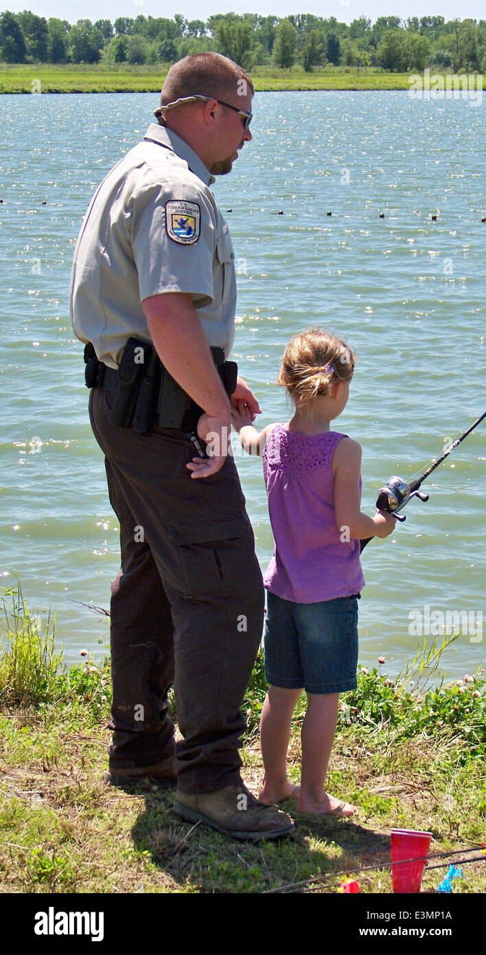 A young girl fishes from the shore of a National Wildlife Refuge. This ...
