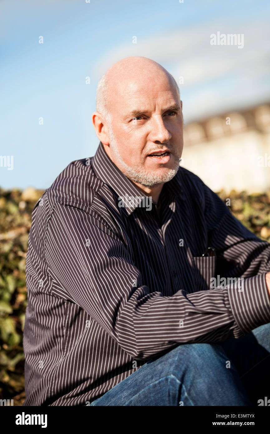 High angle profile view of a balding middle-aged man sitting on a ...