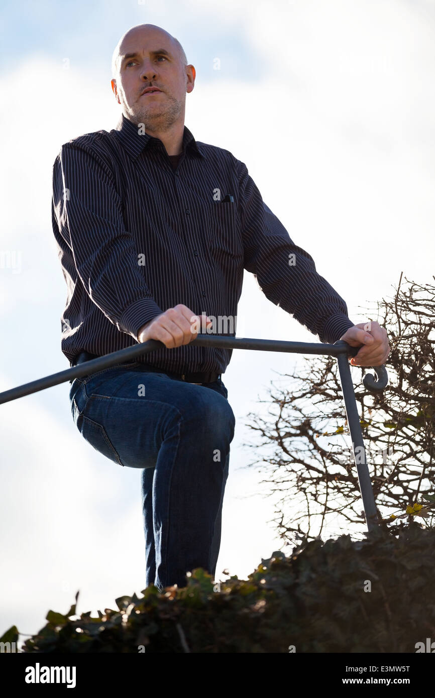View from below of a thoughtful middle-aged man sitting on a flight of ...