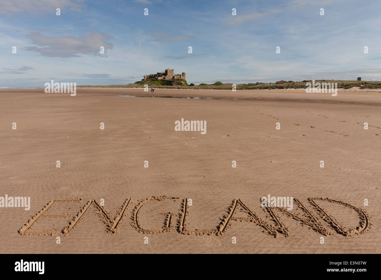 England written in sand on beach at Bamburgh, UK with Bamburgh Castle ...