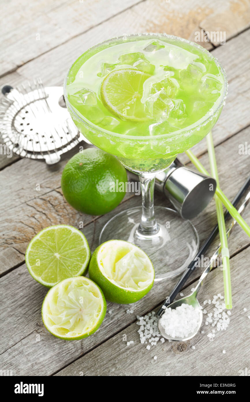 Classic margarita cocktail with salty rim on wooden table with limes ...