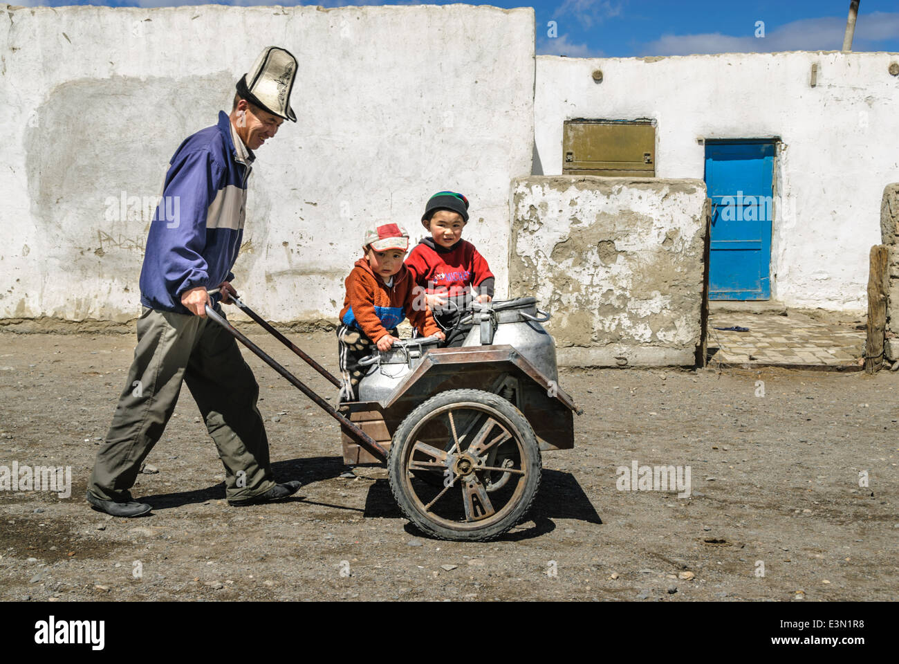 Man with kids carrying water on a wheelbarrow, Karakul lake, Pamir ...