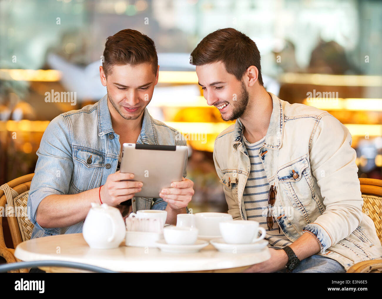 Two young men / students using tablet computer in cafe Stock Photo - Alamy