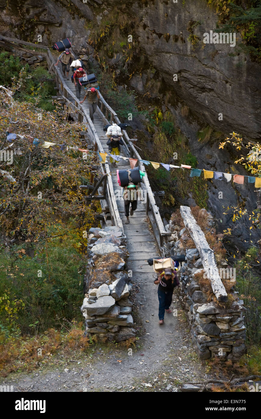PORTERS cross a rickety foot bridge with a 100 foot drop off on either ...