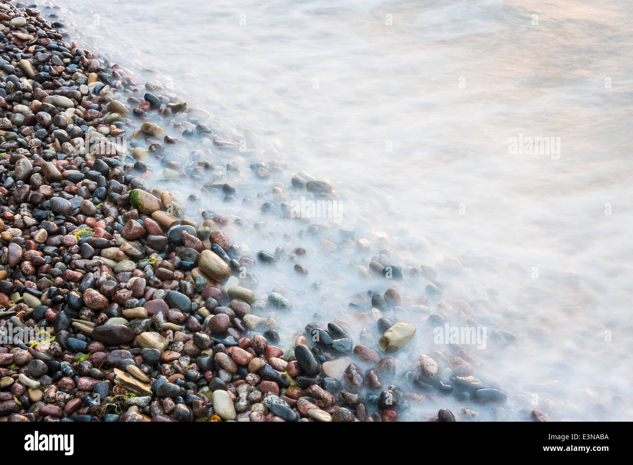 Water waves on small round rocks or stones at a beach Stock Photo - Alamy