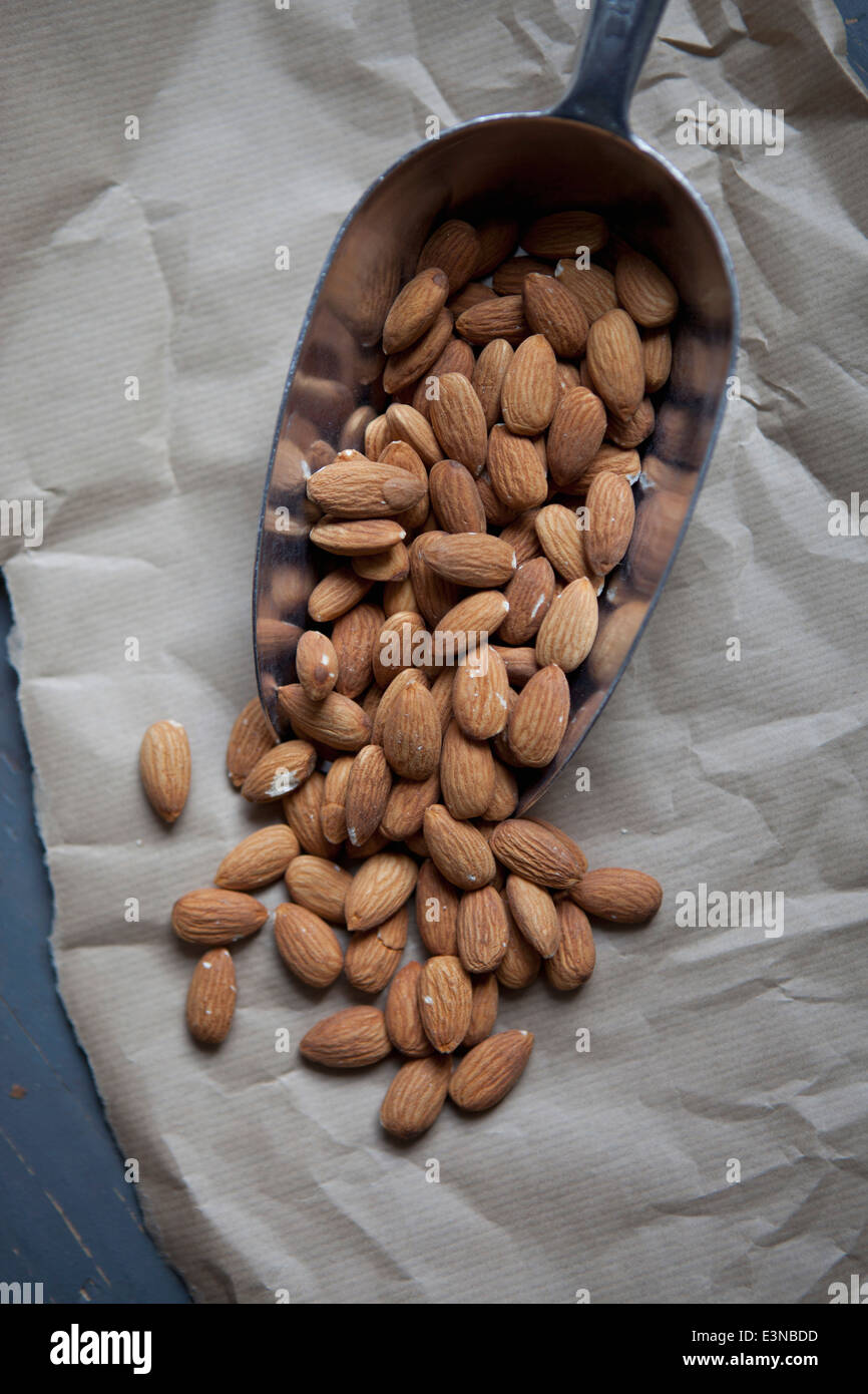 Almonds spilling from scoop on paper Stock Photo - Alamy