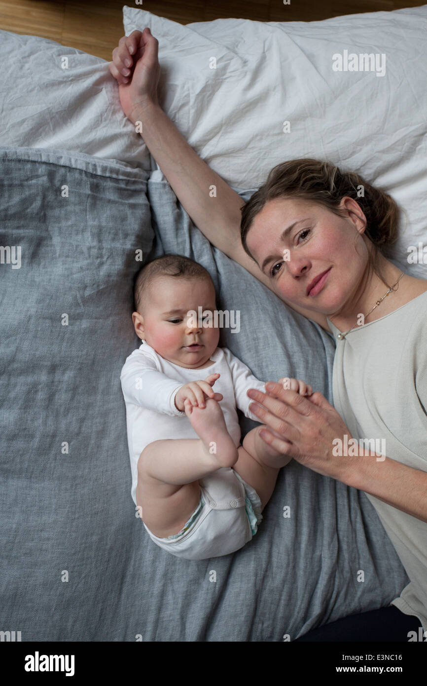 High angle portrait of mother with baby girl lying on mattress Stock ...