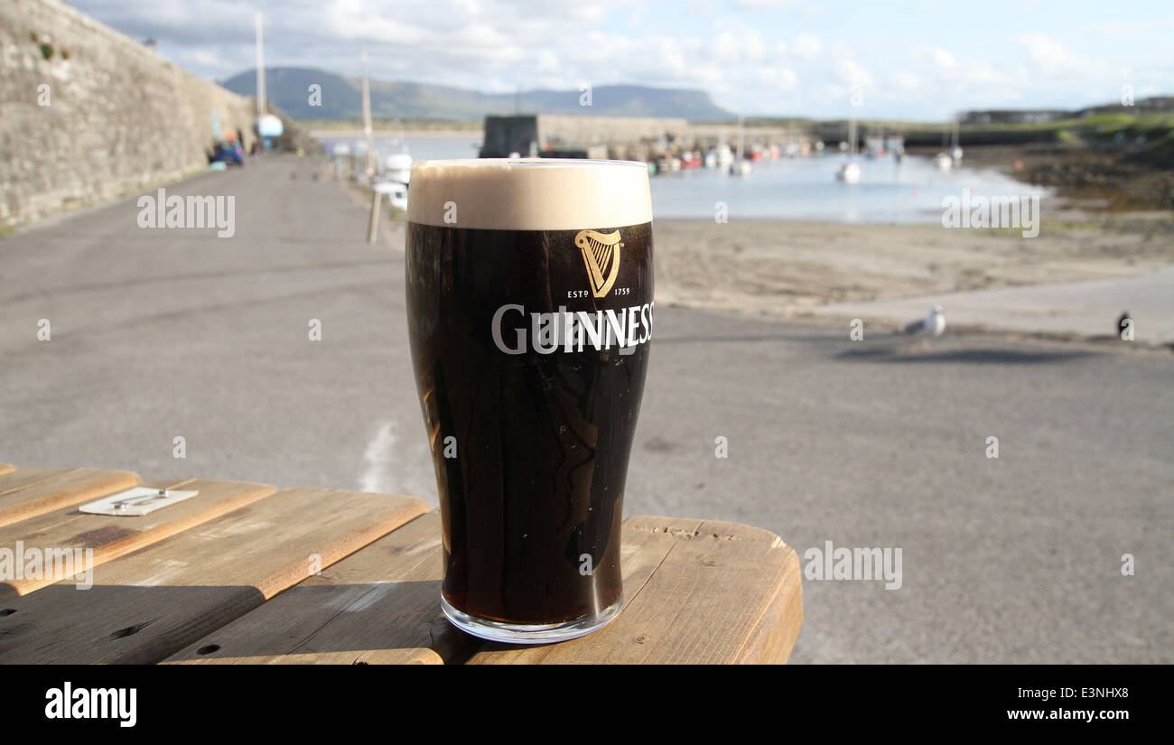 A pint of Guinness on a table outside a pub in Ireland with boats and ...