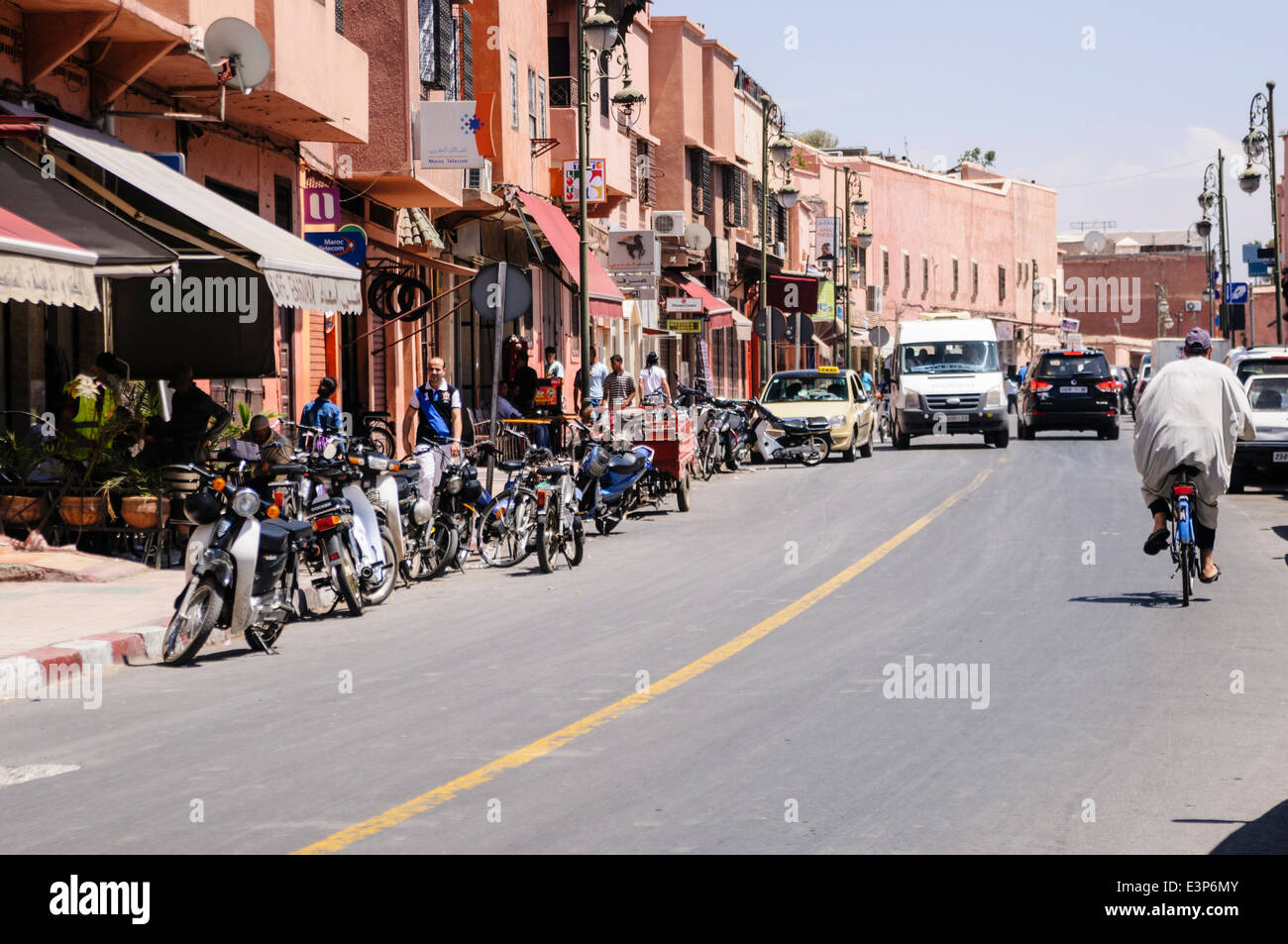 Typical street in Marrakech, Morocco with parked scooters cars and vans ...