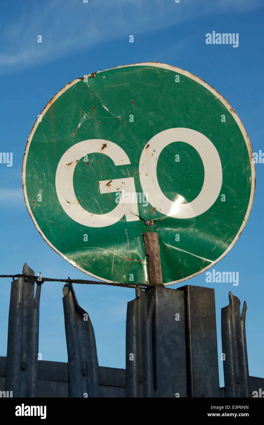 Metaphor. Positive concept. A circular GO sign, battered and worn, with ...