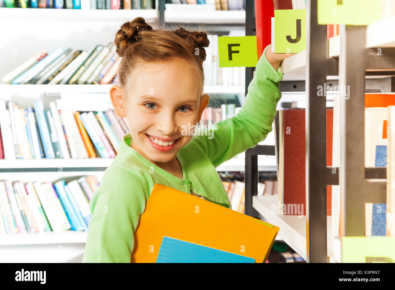 Smiling girl searching books in library Stock Photo - Alamy