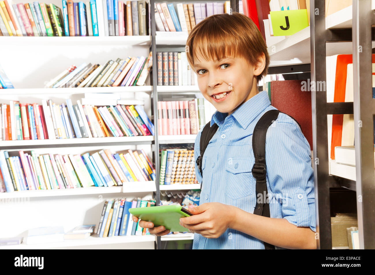 Cute boy stands and holds books in library Stock Photo - Alamy
