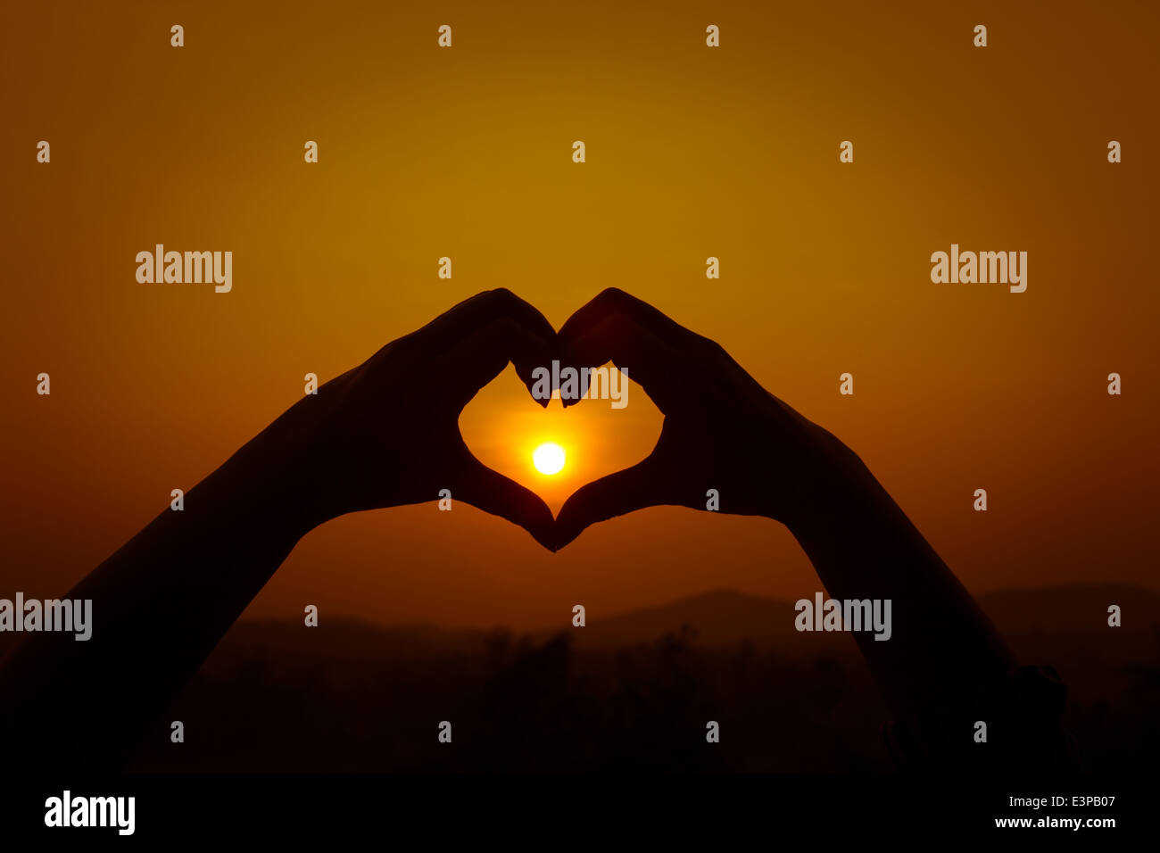 Silhouettes hand heart shaped with sun sets and the sky orange Stock ...