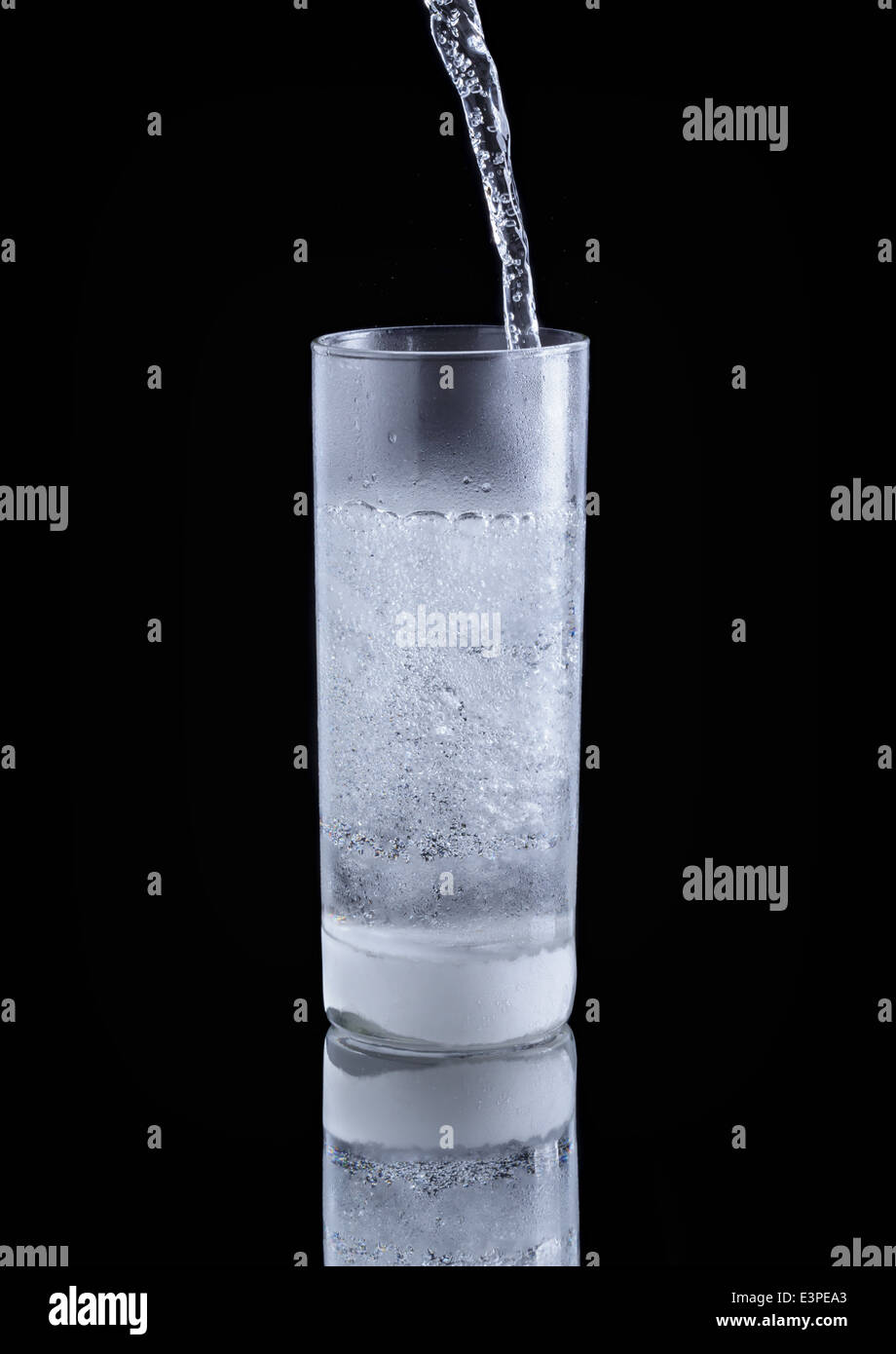 pouring cold water in simple highball glass, on black background Stock Photo - Alamy