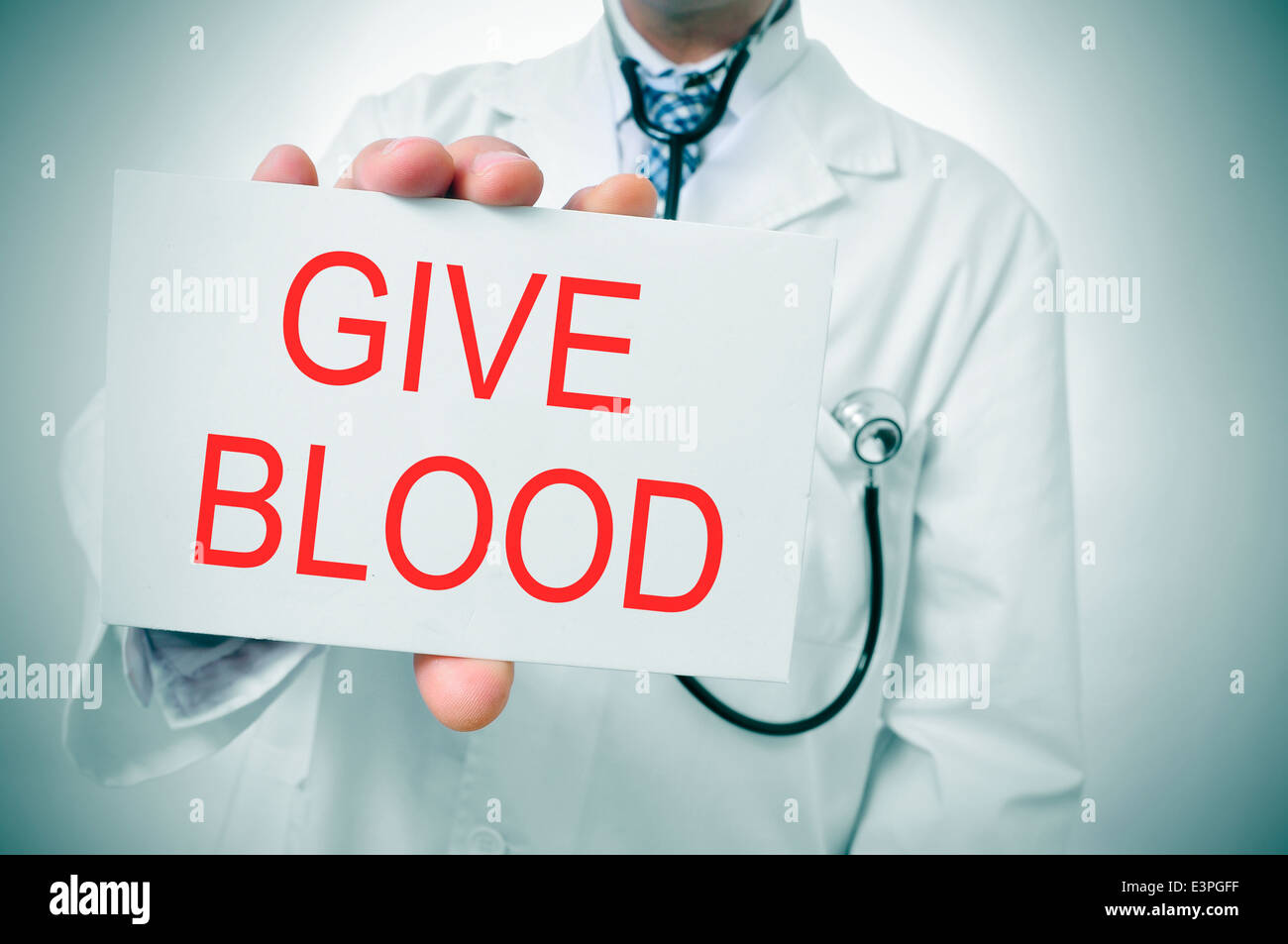 a doctor showing a signboard with the sentence give blood written in it ...