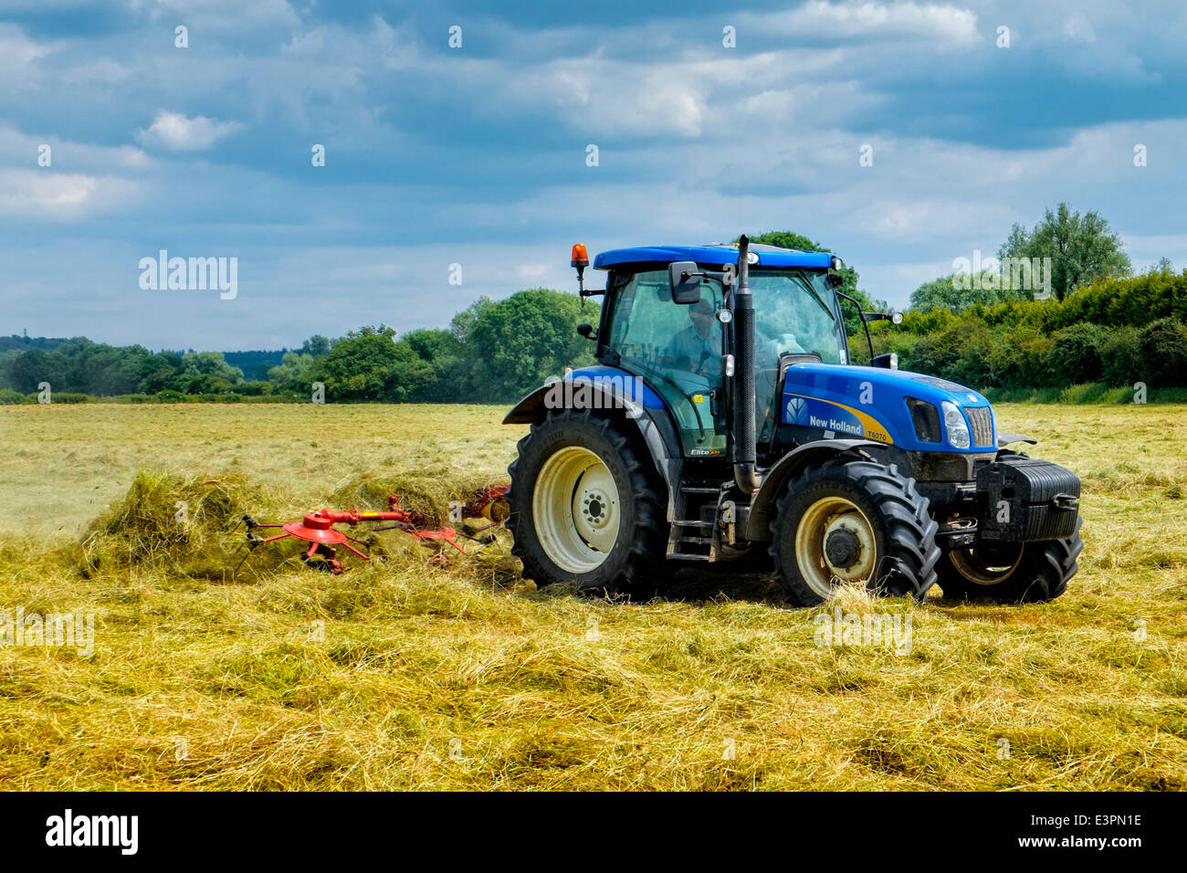 Farmer turning cut hay with a tractor Stock Photo - Alamy