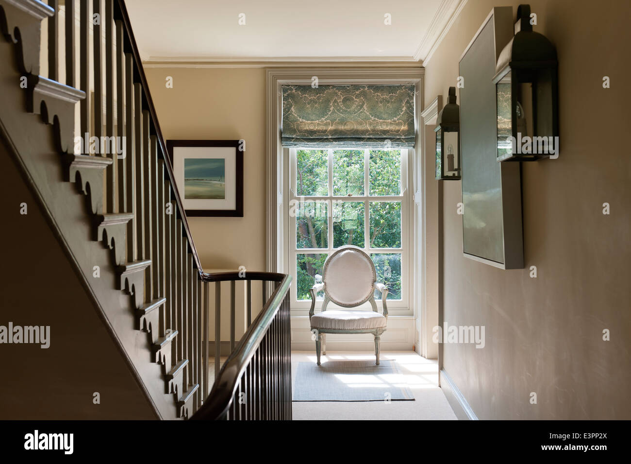 Round back French armchair on staircase landing with large paned window ...