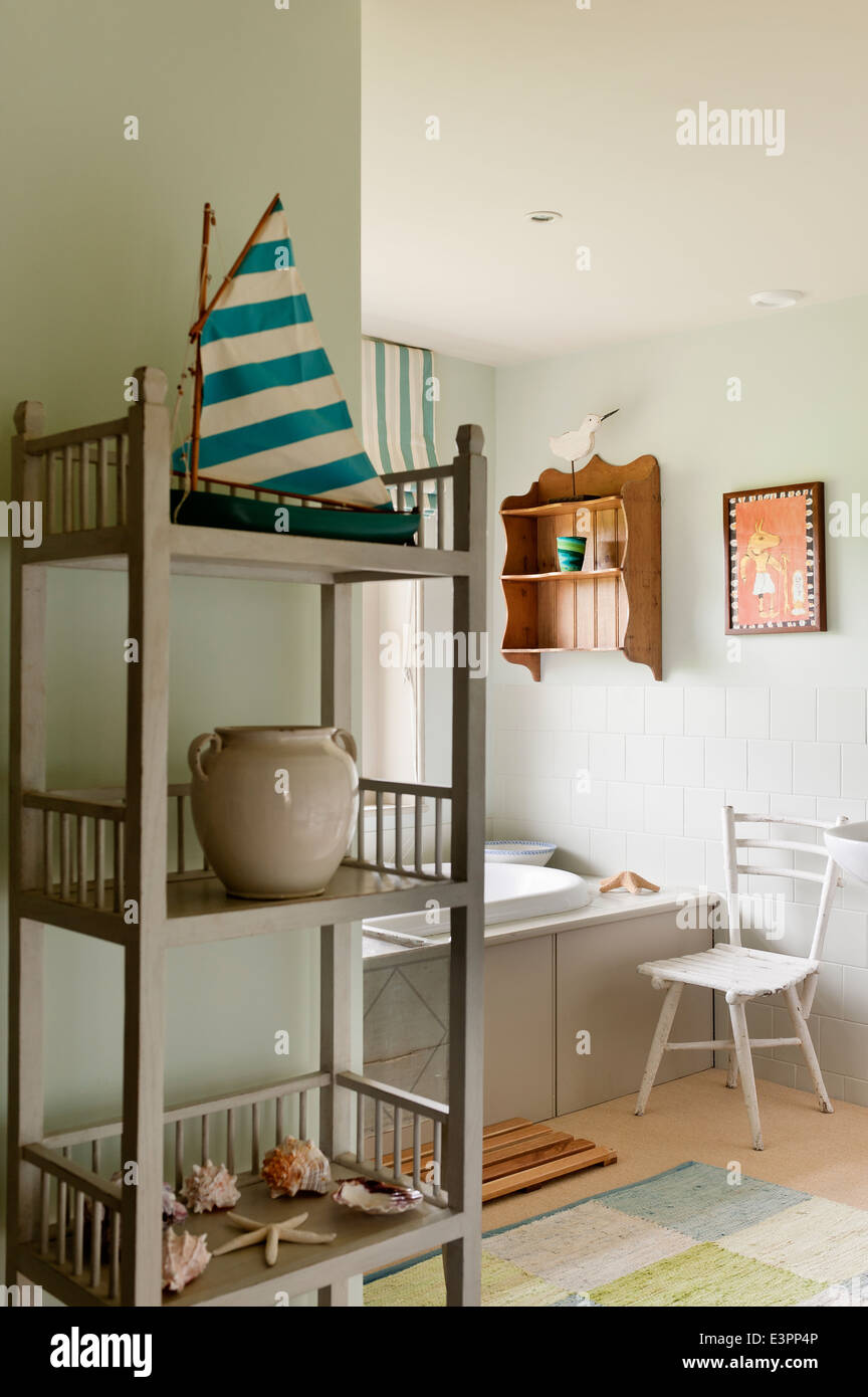 Wooden shelf in marine themed bathroom with sea shells and model boat ...